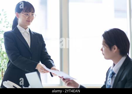 Woman handing materials to her boss Stock Photo - Alamy