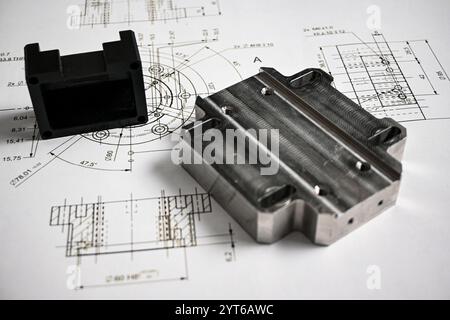 Plastic and metal prototypes are lying on a technical drawing with ...