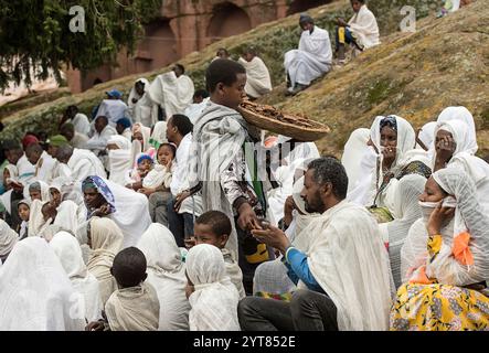 Altar boy distributes blessed bread to worshippers in traditional white ...