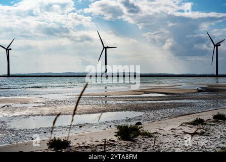 Wind turbine by the sea with glittering sunshine sun and blue sky ...