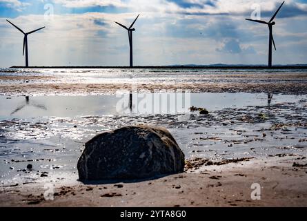 Wind turbine by the sea with glittering sunshine sun and blue sky ...