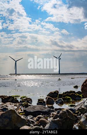 Wind turbine by the sea with glittering sunshine sun and blue sky ...