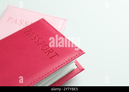 Passports in color covers on light blue background, top view. Space for ...