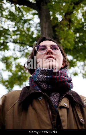 Young woman wearing autumn coat walking with smartphone and coffee cup ...