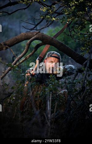 Hunter man standing in bushes nearby marshland in expectation of ...