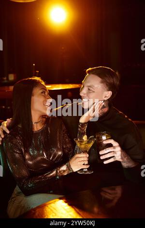 A young couple shares laughter and drinks, enjoying their lively night ...