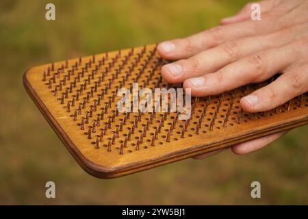 Sadhu board with nails are held by a man between two hands. Acupuncture ...