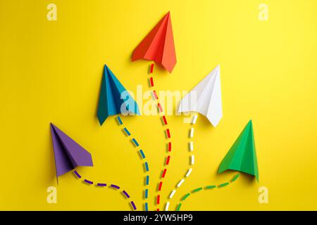 Colorful paper planes with flight paths on orange background. Dashed ...