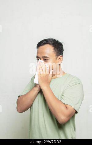 Asian man blowing nose on sofa at home for cold and flu relief Stock ...