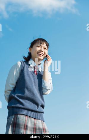 Female high school student Blue sky Smart phone Stock Photo - Alamy