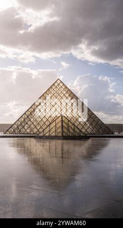 Louvre pyramid under the sun with the ground wet after a day of rain ...