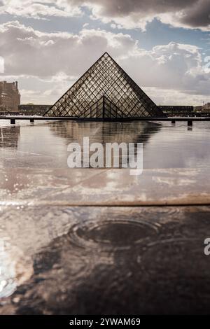 Louvre pyramid under the sun with the ground wet after a day of rain ...