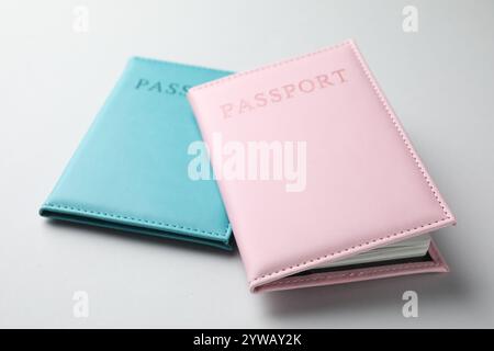 Passports in color covers on light background, top view. Space for text ...