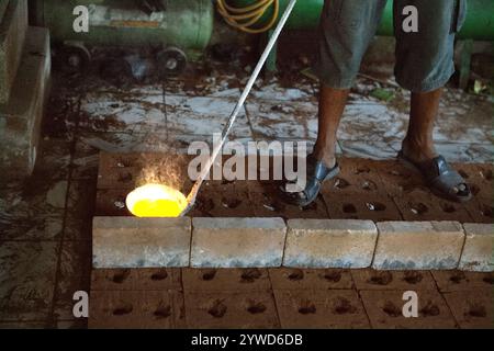A worker molding liquid metal as a part of production process in the ...
