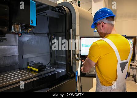 Metalworker wearing safety glasses and hardhat using cnc milling ...
