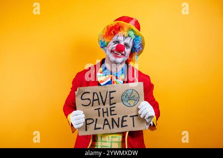 Smiling clown holding "Save the Planet" sign Stock Photo - Alamy