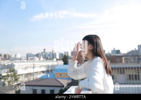Woman shouting on rooftop with hand in front of mouth Stock Photo - Alamy