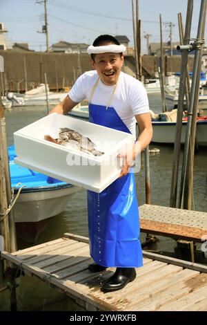 Fresh fish shopkeeper carrying a box of fish at the harbour Stock Photo ...