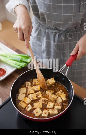 Woman stir-frying minced meat, tofu and seasoning Stock Photo - Alamy