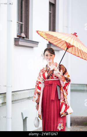 A Japanese woman in her 20s wears a red kimono (hakama), a staple of ...
