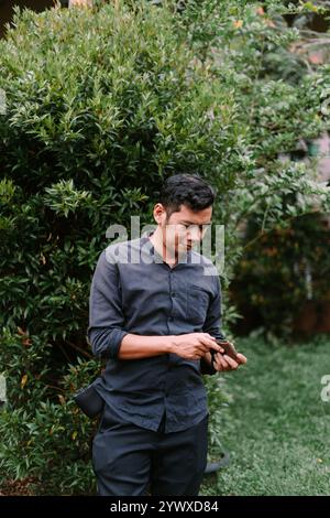 Young latin man holding wallet with dollars sitting on sofa at home ...