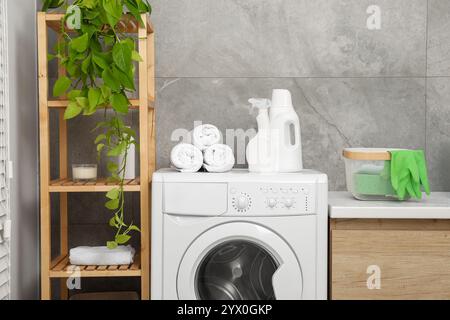 Shelving unit with towels, detergent and washing machine near light ...
