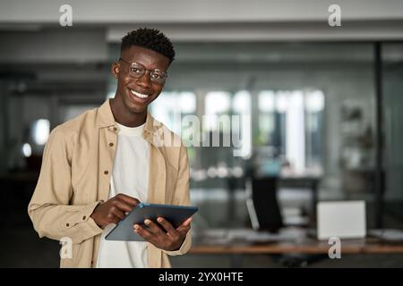 Happy businessman using tablet computer while leaning on desk in office ...