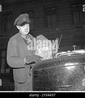 Wood gas 1942. A man fills more coal into the container to fuel the ...