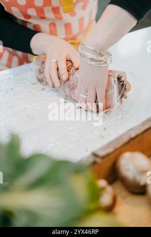 Woman wrapping fresh bread with baking paper on white wooden background ...