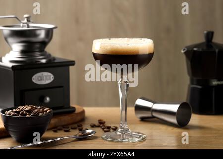 Glass of delicious espresso martini, jigger, shaker and coffee beans on ...