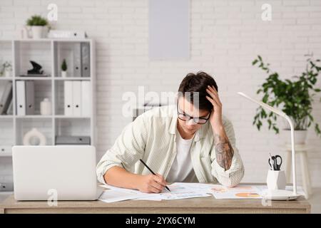 Male economist working with diagrams at table in office Stock Photo - Alamy