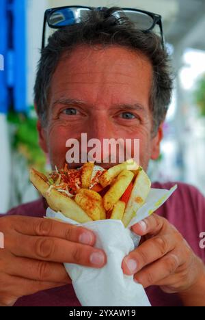 Man eating a kebab and chips Stock Photo - Alamy
