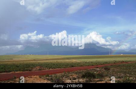 Rainbow view of dirt road and tepui mountains across savannah, Gran ...