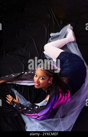 Teenage brunette girl in fetal position dressed in butterfly wings ...