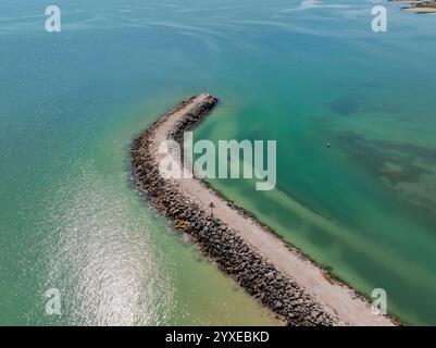 Aerial view of a curved breakwater leading into a coastal marina at ...