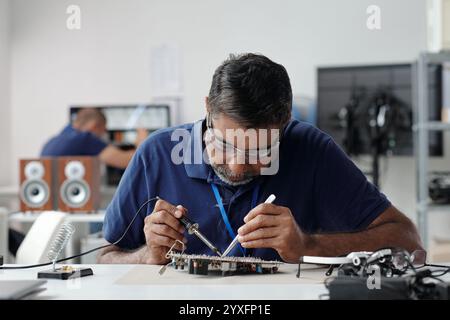Technician testing electronic components and wiring inside disassembled ...