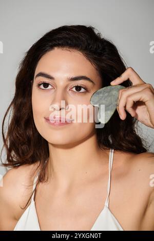 Beautiful young woman with massage tool on color background Stock Photo ...