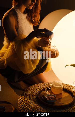 A young girl conducts an evening tea drinking procedure indoors ...