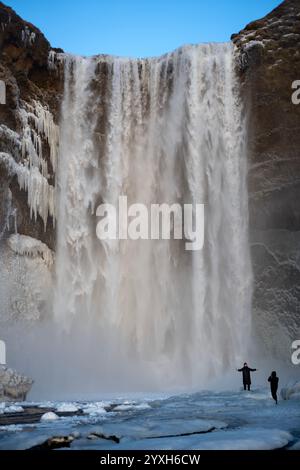 Visitors stand along the frozen and ice covered waters bellow the ...