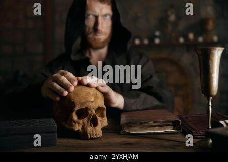 Mystical spooky medieval monk in black cassock with human skull on ...