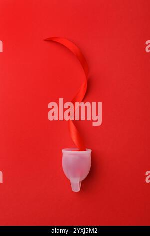 Menstrual cup with ribbon on color background Stock Photo - Alamy