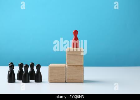 Human figures in front of stacked wooden blocks with red figure on top ...