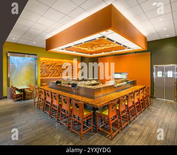 Sushi restaurant with large square sushi bar and sushi chef behind bar ...