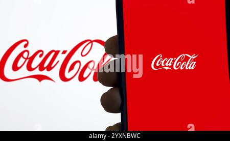 Coca-Cola logo is seen on a mobile phone and a computer screen Stock ...