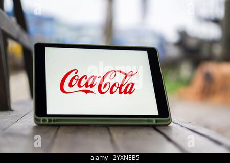 Coca-Cola logo is seen on a mobile phone and a computer screen Stock ...