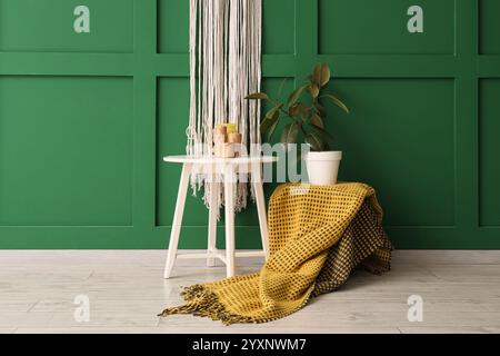 Coffee table with houseplant and blanket on armchair near brown wooden ...