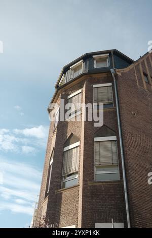 A red brick building with a slanted roof. The building is old and has a ...