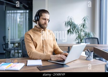 Image of focused man in headphones playing video game on computer while ...