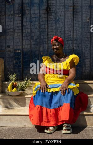 A Palenquera Woman Sitting On Stone Steps Wearing A Bright Dress in ...
