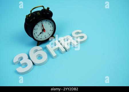 36 Hrs alphabet letters and alarm clock top view on pink background ...